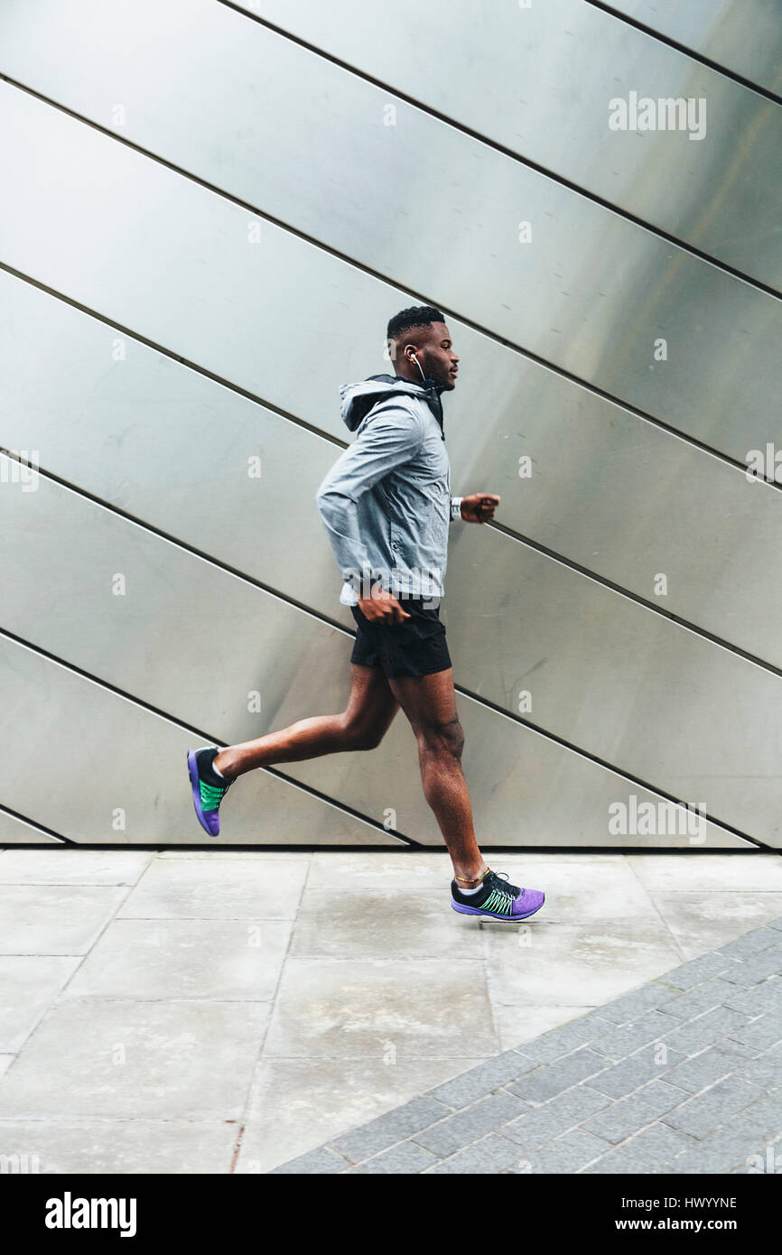 Young man running along building front Stock Photo - Alamy