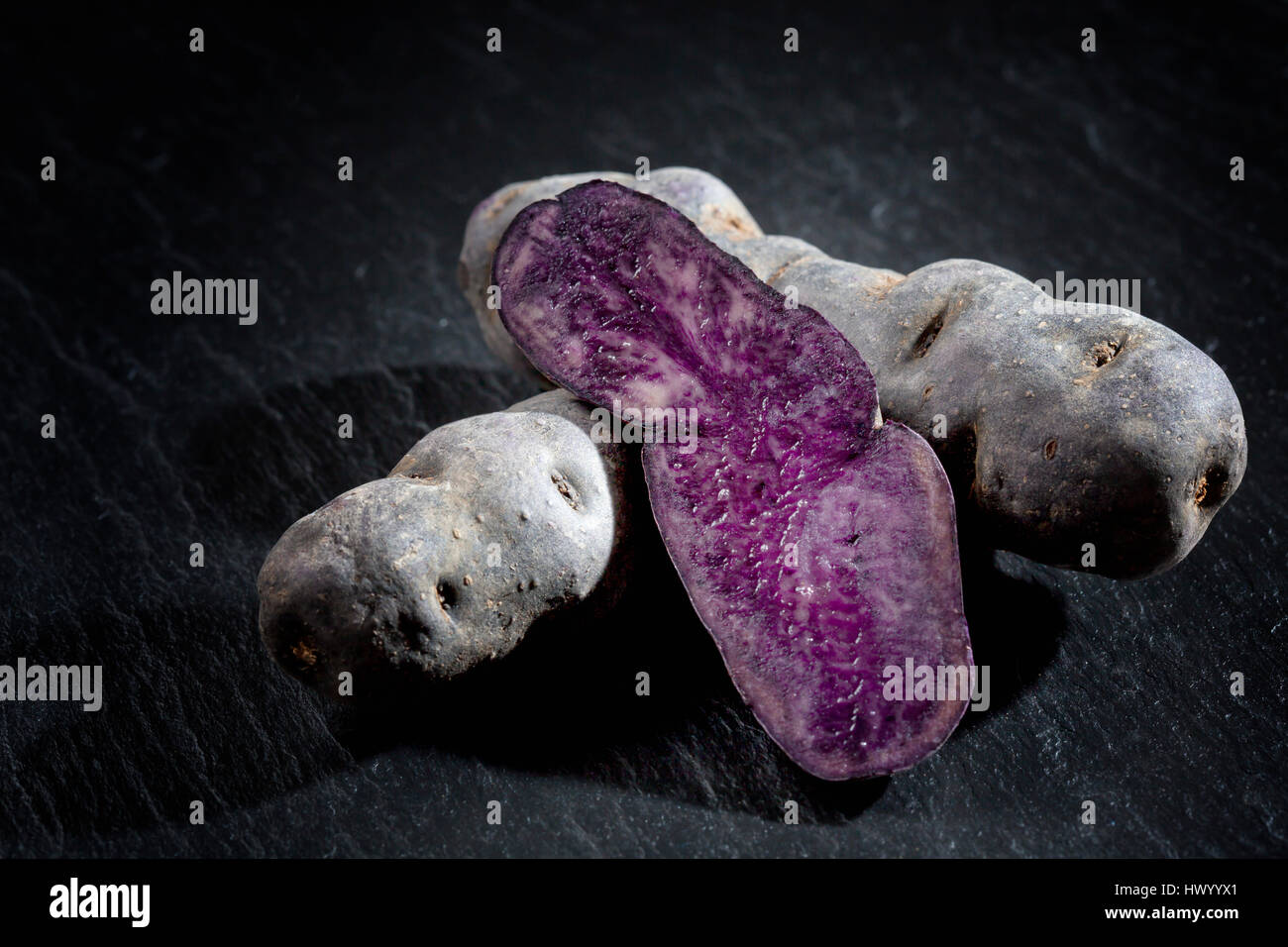 Whole and sliced purple potatoes on slate Stock Photo - Alamy