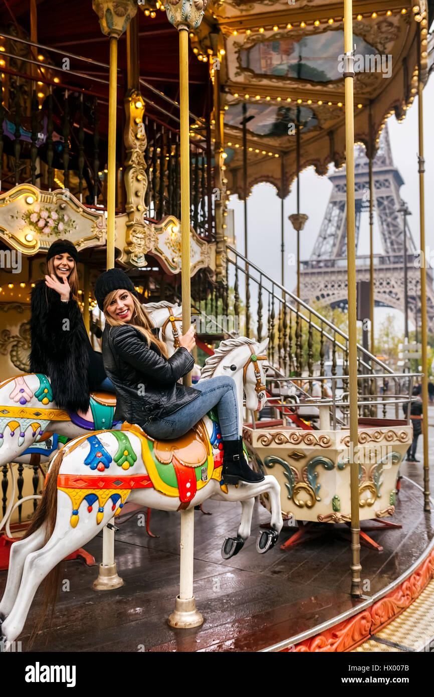 France, Paris, two best friends riding a carousel with the Eiffel Tower ...