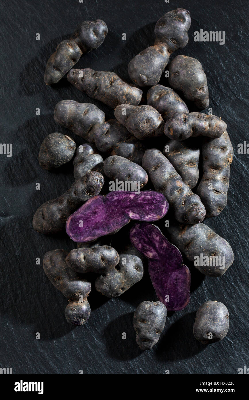 Whole and sliced purple potatoes on slate Stock Photo - Alamy