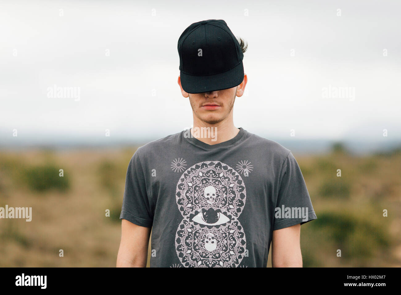 Young man covering his face with a basecap Stock Photo - Alamy