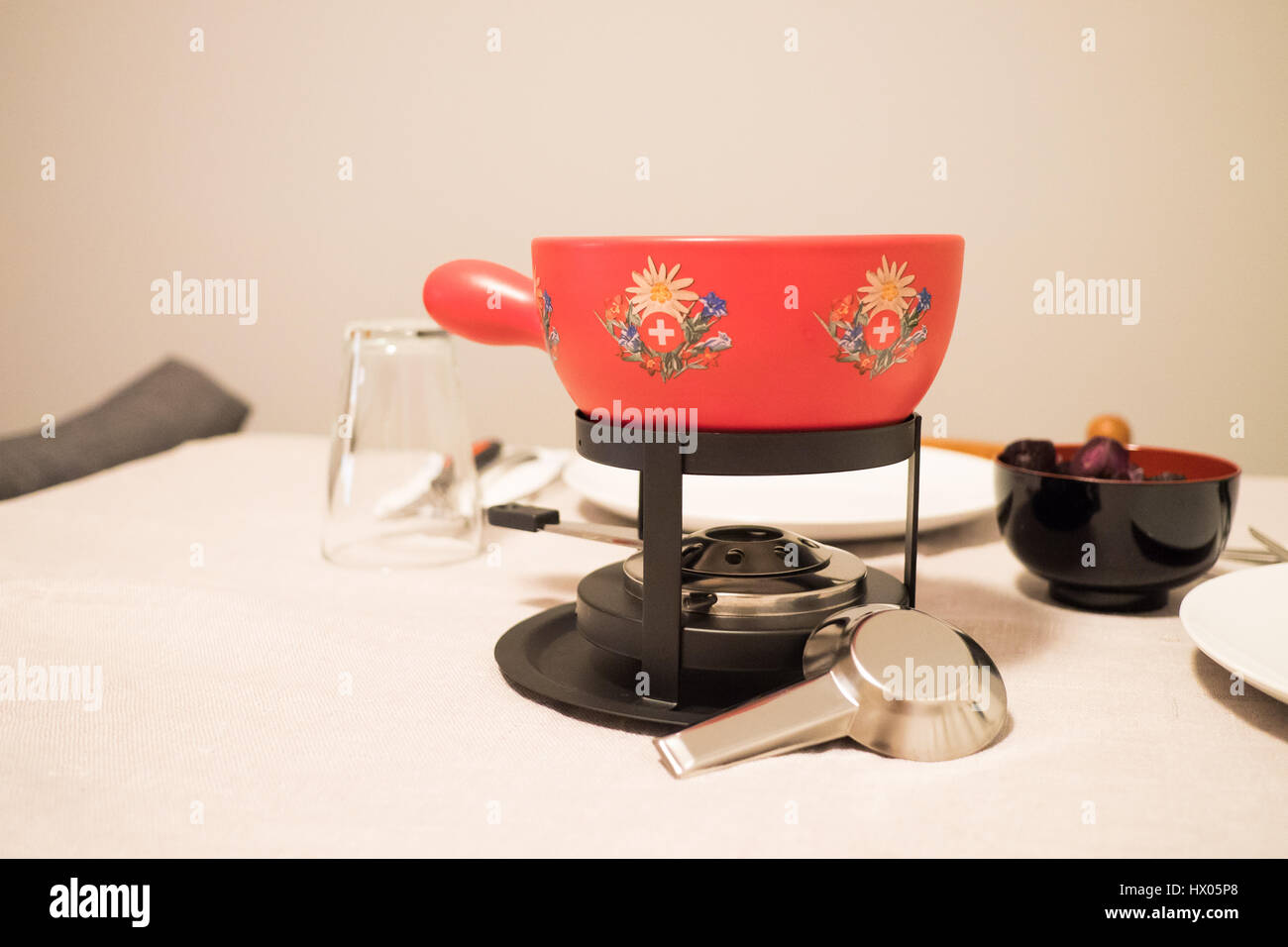 Red Swiss fondue pot on a table Stock Photo - Alamy