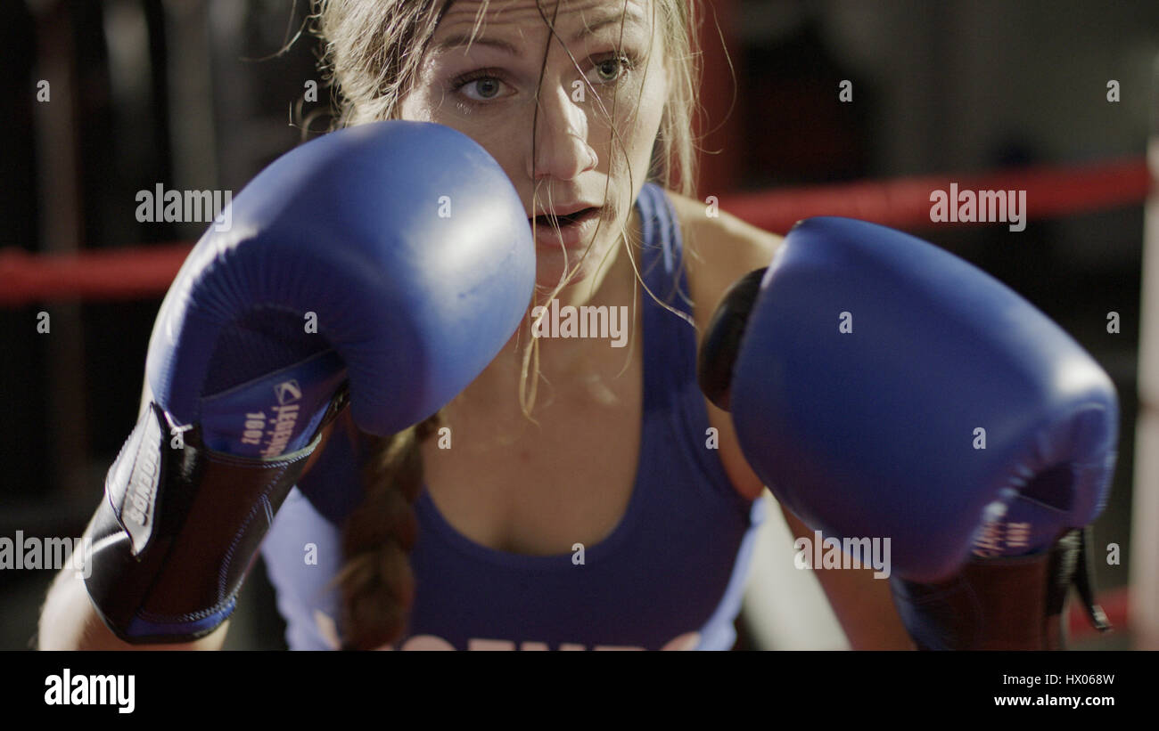Close up of female boxer in boxing gloves standing in boxing ring ...