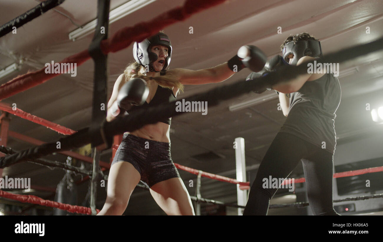 Low angle view of female boxers punching and fighting in boxing ring ...