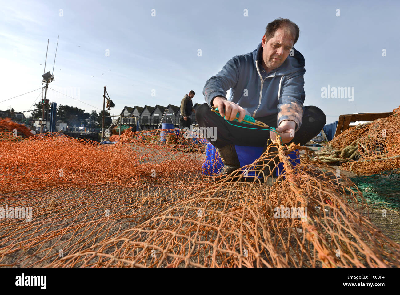 Fisherman in Whitstable, Kent, UK mending nets by hand Stock Photo - Alamy