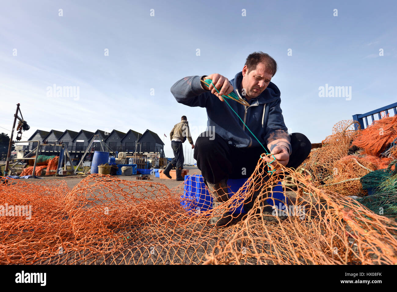 Fisherman in Whitstable, Kent, UK mending nets by hand Stock Photo - Alamy