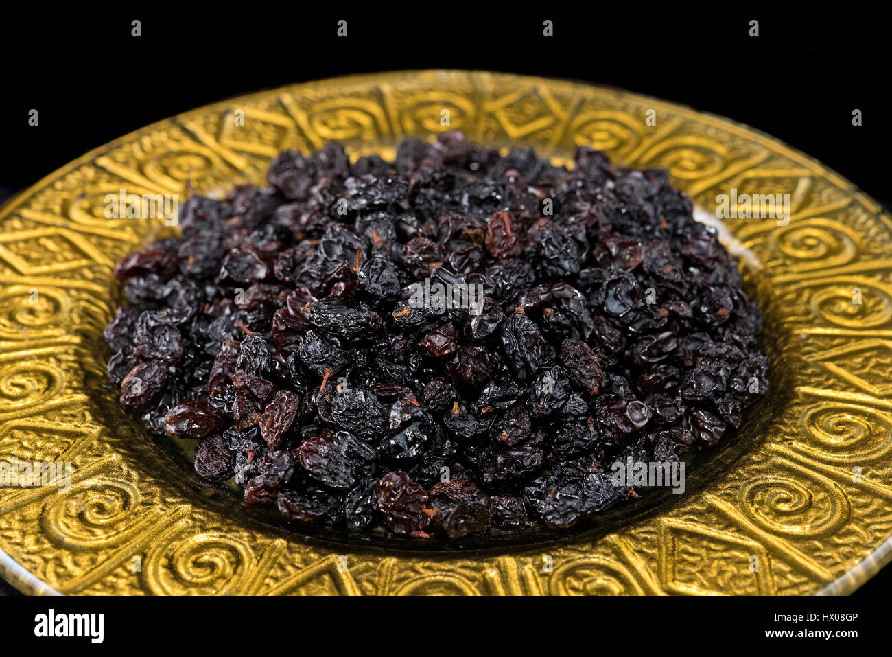 Black raisins in golden plate Stock Photo - Alamy