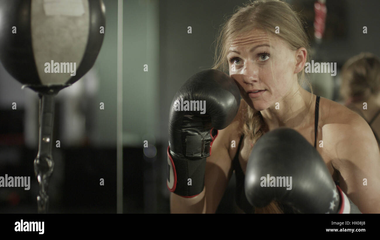 Close up of female boxer working out and training with punching ball in ...