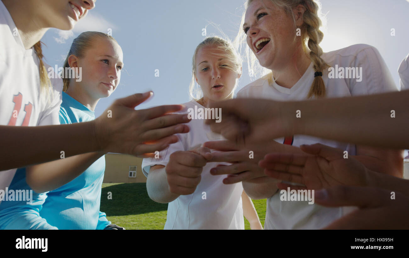 Low angle blurred view of soccer team players cheering in huddle before ...