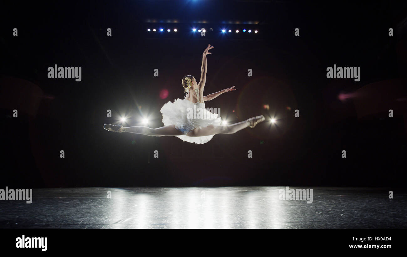 Rear view of serious ballet dancer leaping in costume performing ...