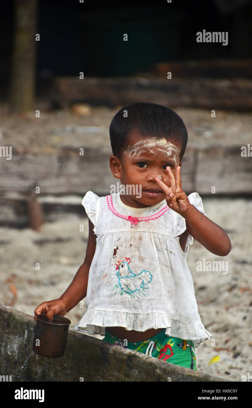 A Moken child plays with a cup in an old canoe in the village of ...