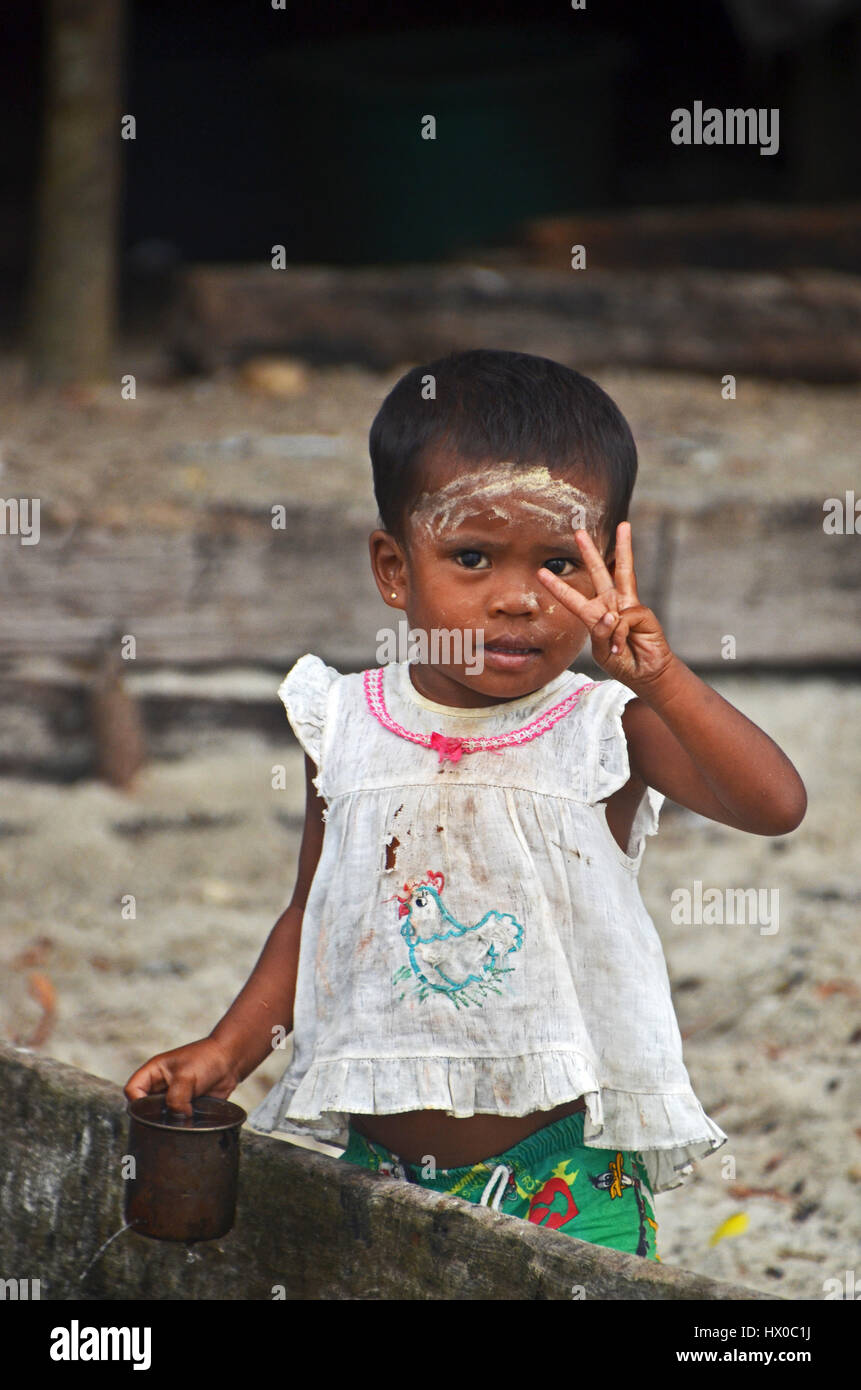 A Moken child plays with a cup in an old canoe in the village of ...