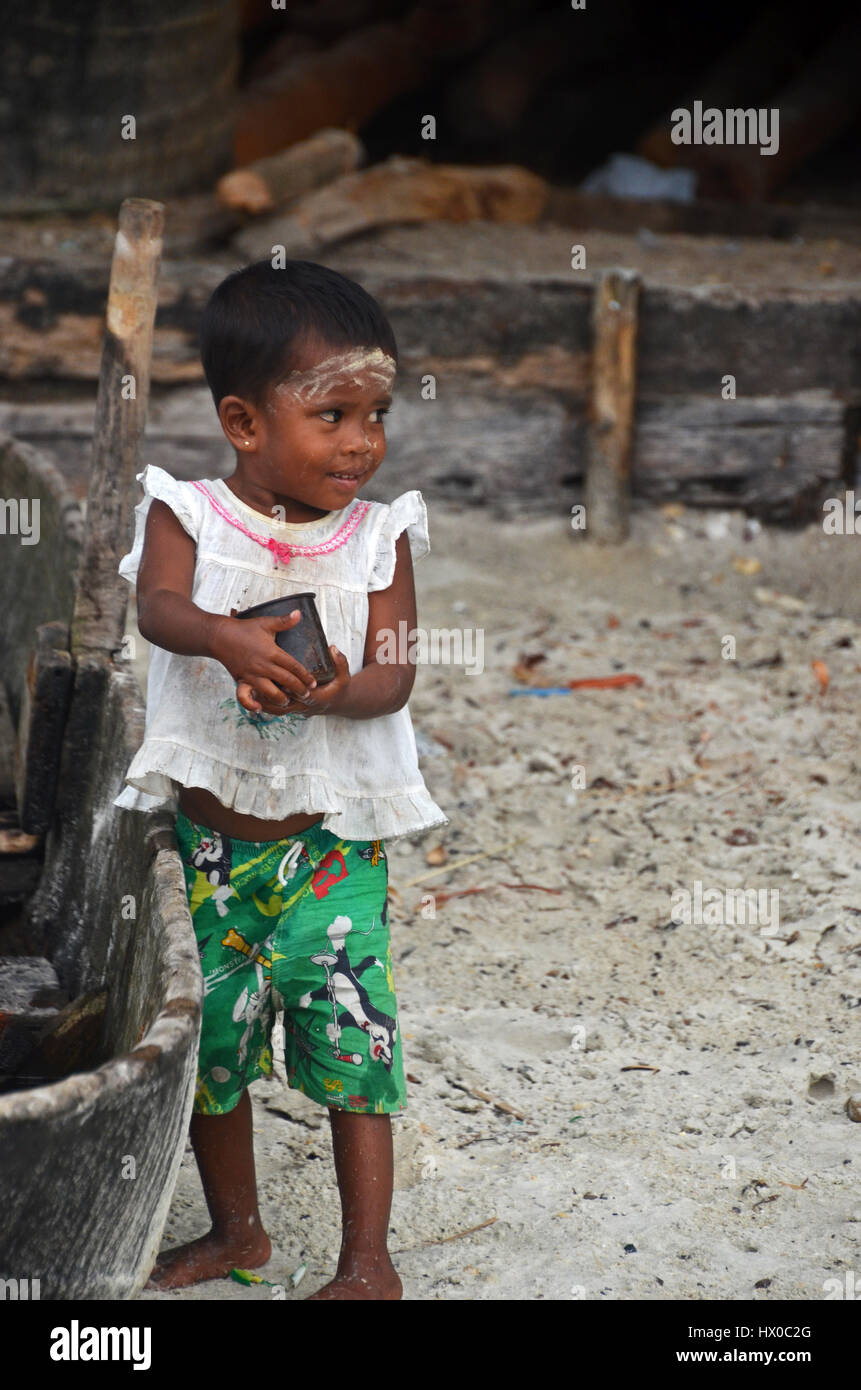 A Moken child plays with a cup in an old canoe in the village of ...