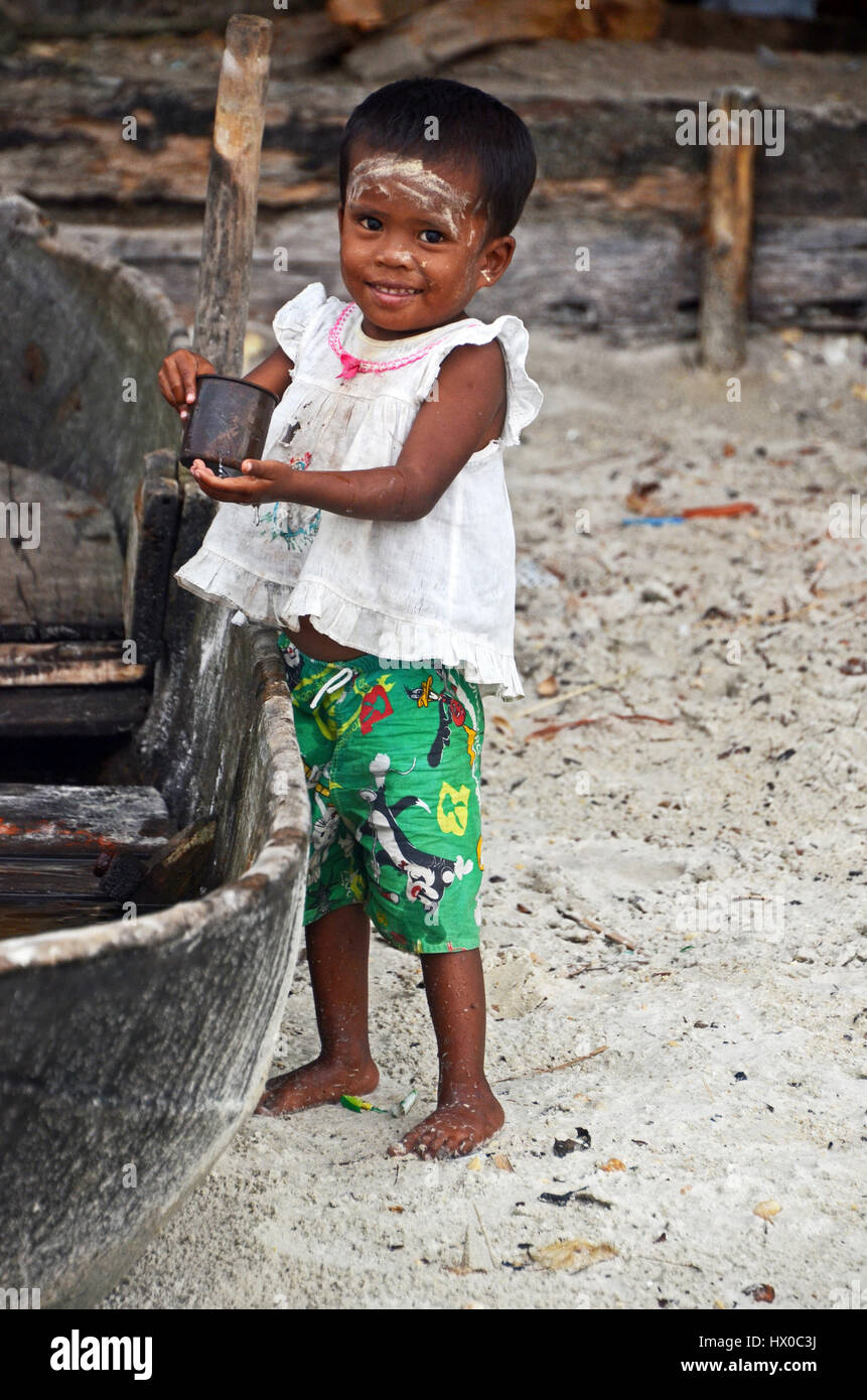 A Moken child plays with a cup in an old canoe in the village of ...