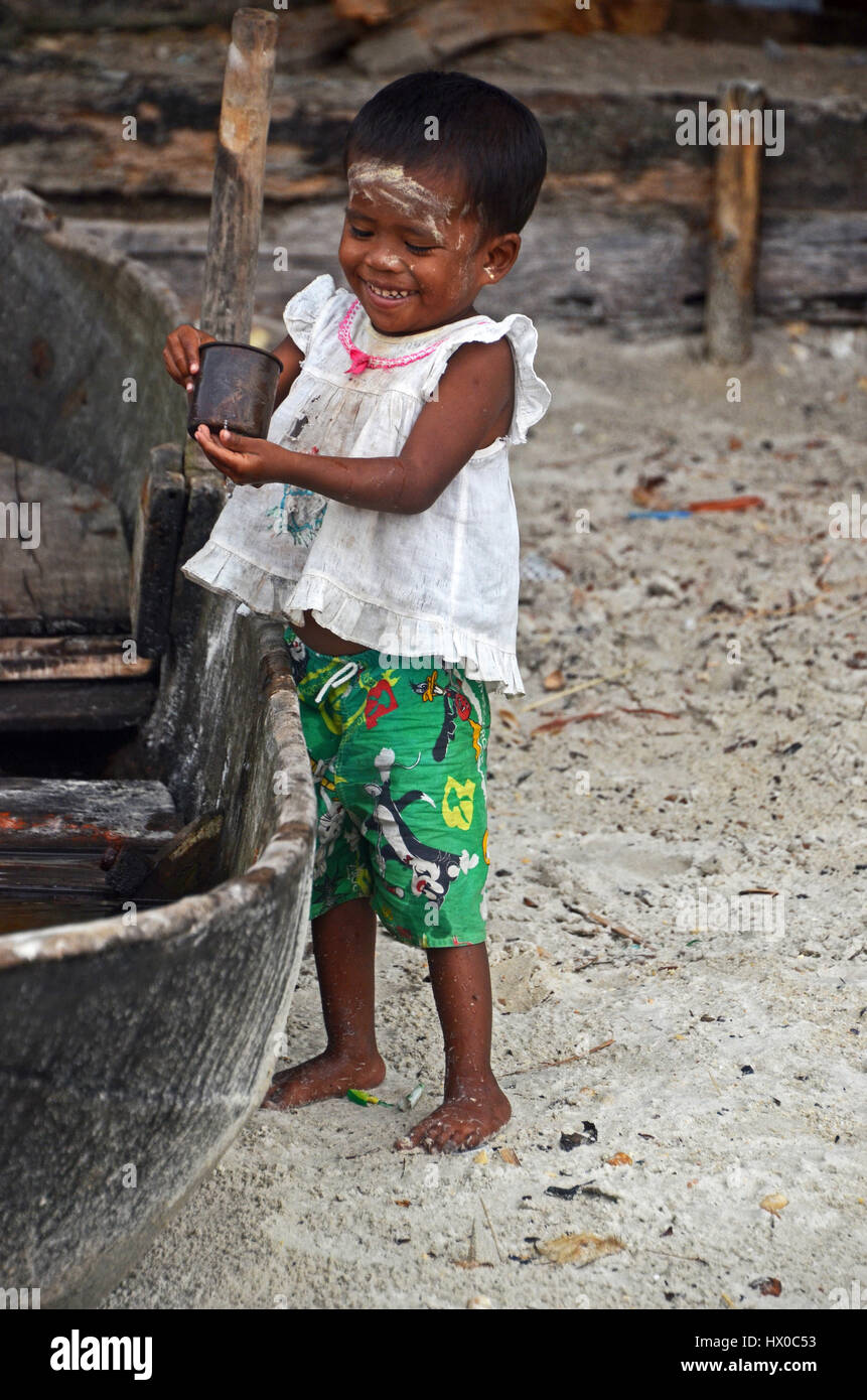 A Moken child plays with a cup in an old canoe in the village of ...