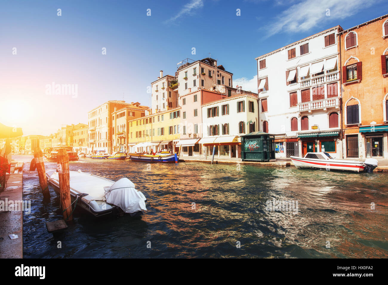Green water channel with gondolas and colorful facades of old medieval ...