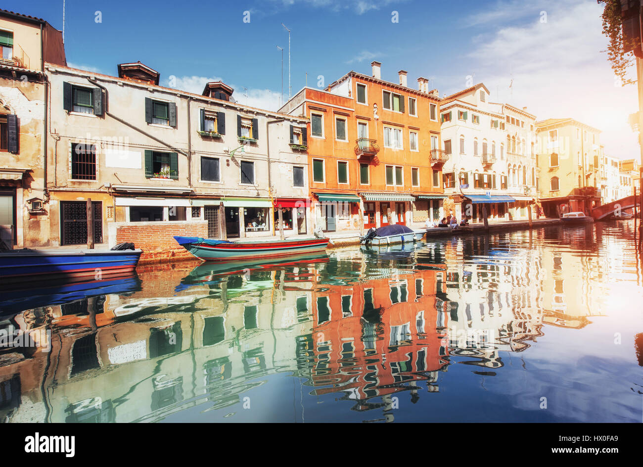 Green water channel with gondolas and colorful facades of old medieval ...