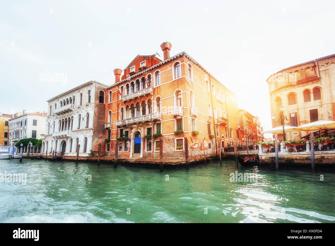 Green water channel with gondolas and colorful facades of old medieval ...