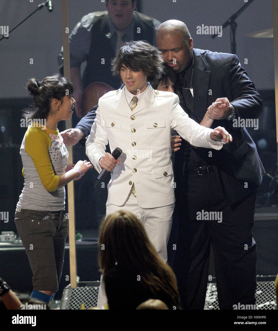 Fans are escorted off the stage by security as lead singer Joe Jonas ...