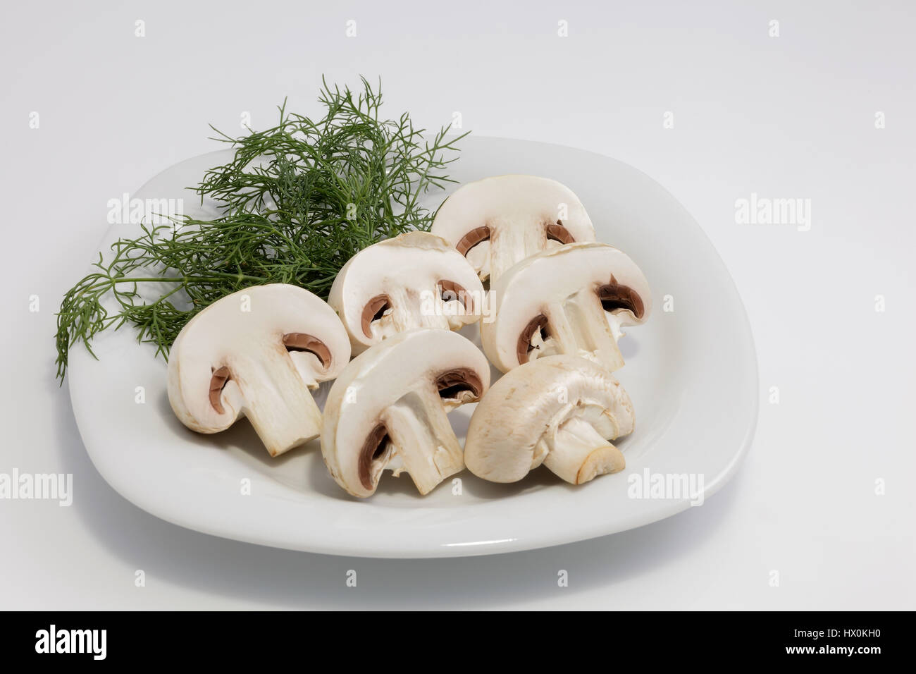 Cut champignons on a plate with greens. Close-up Stock Photo - Alamy
