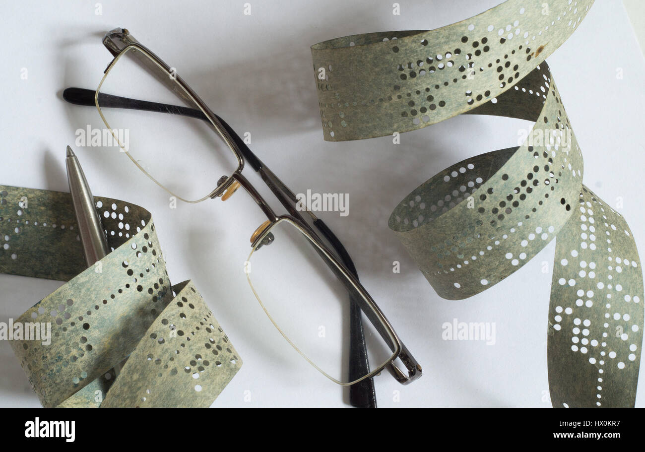 Strips of old punched tape on white surface Stock Photo - Alamy