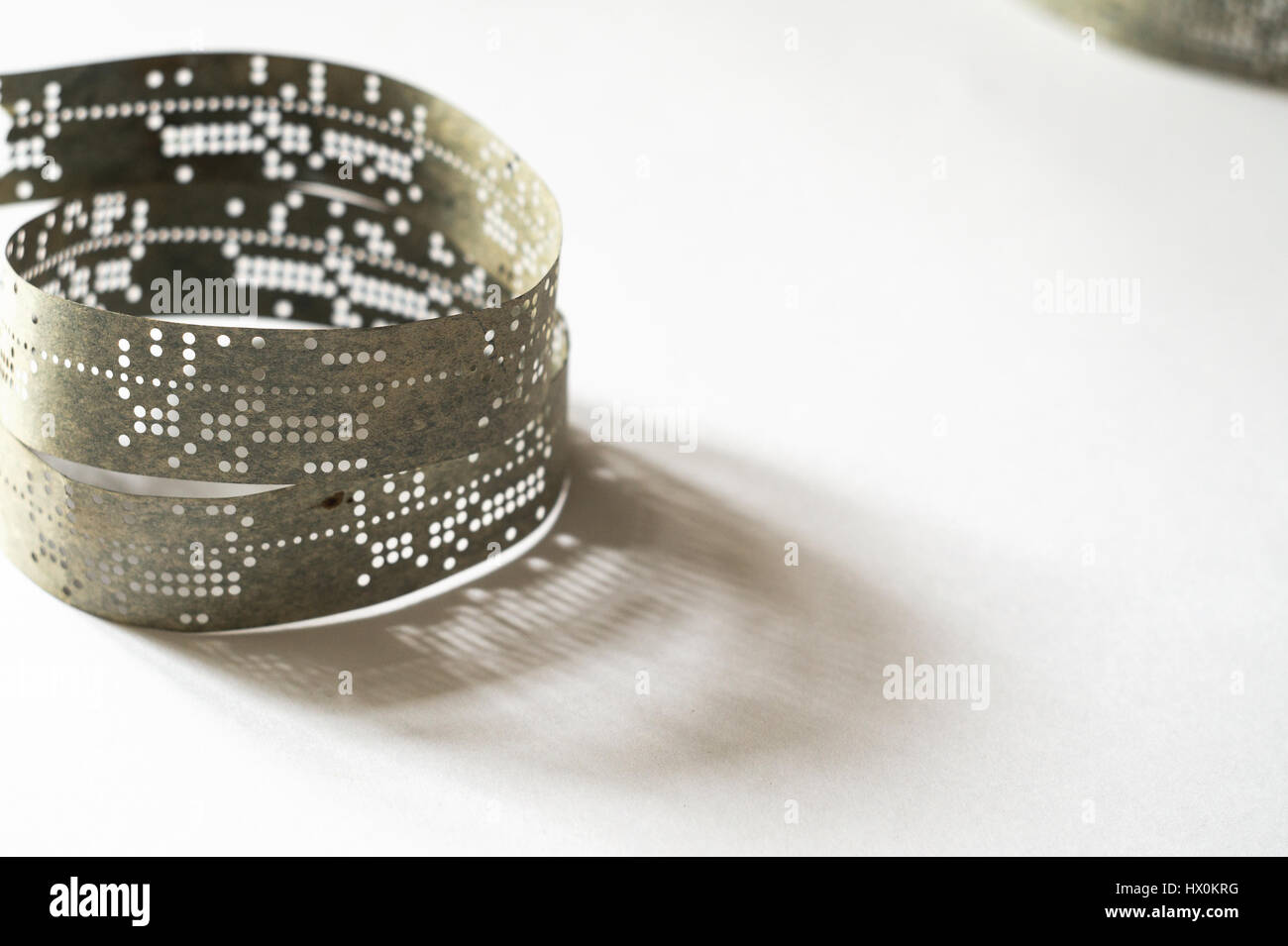 Strips of old punched tape on white surface Stock Photo - Alamy