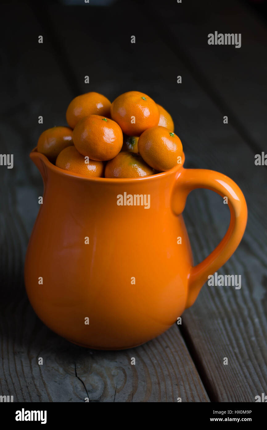 Bright orange pitcher filled with tangerines Stock Photo - Alamy