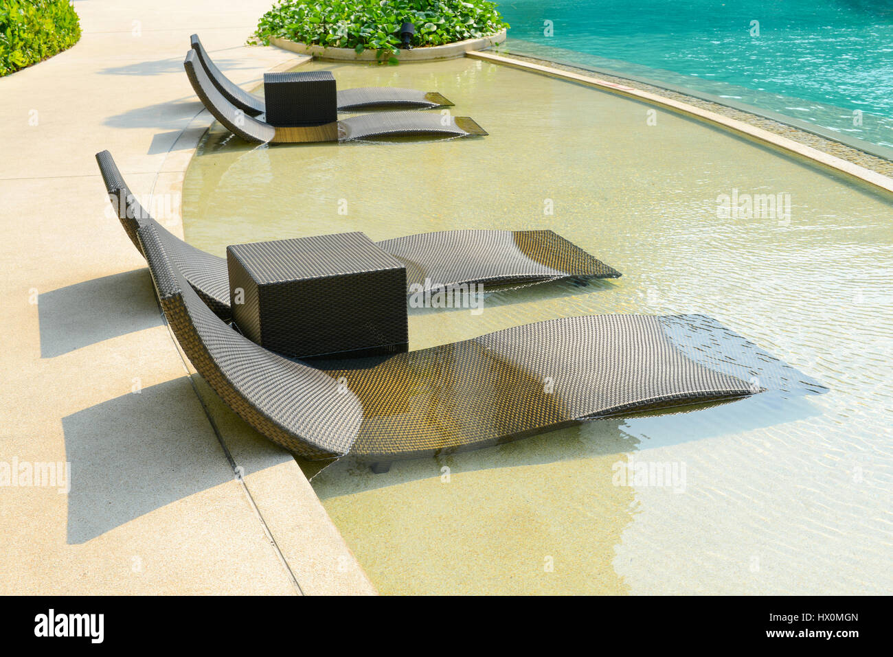 Beach chairs in luxury swimming pool at tropical hotel resort, relaxing ...