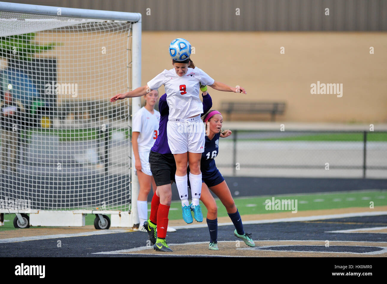 In a defensive move, player heads a ball out from in front of her goal ...