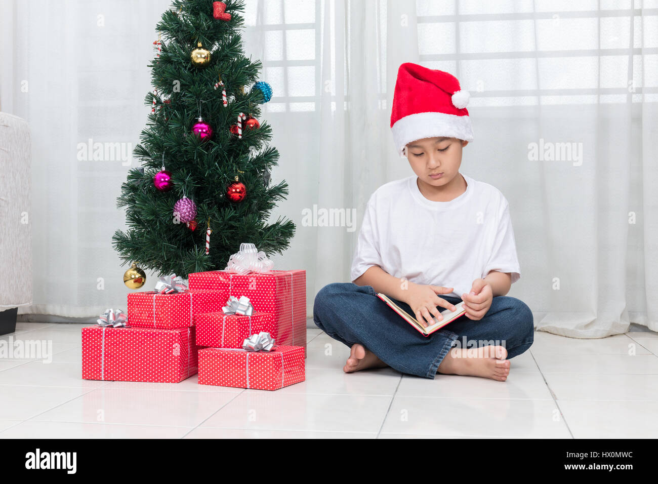 Asian Chinese little boy reading book beside Christmas presents Stock ...