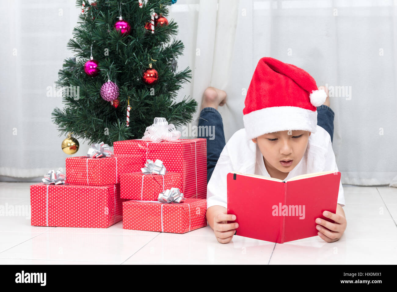 Asian Chinese little boy reading book beside Christmas presents Stock ...