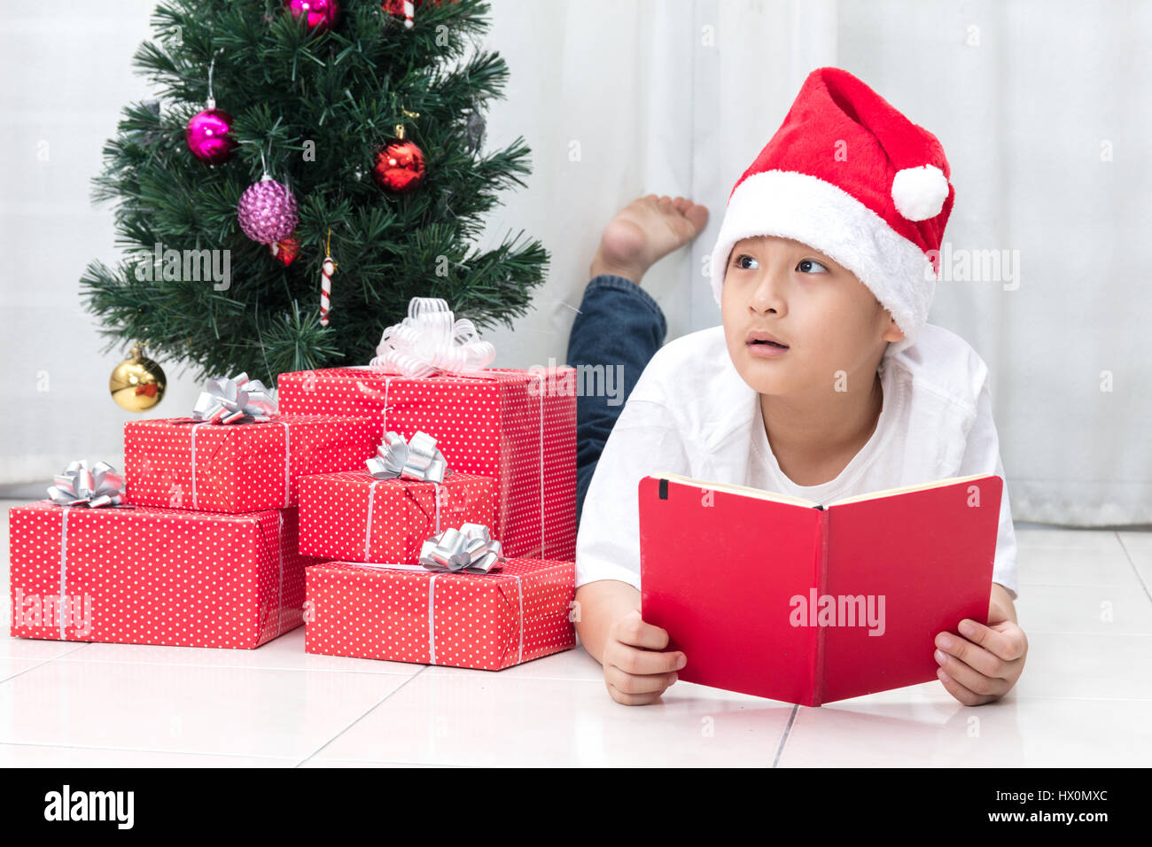 Happy Asian Chinese little boy reading book beside Christmas presents ...