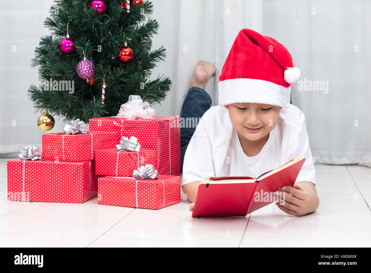 Happy Asian Chinese little boy reading book beside Christmas presents ...