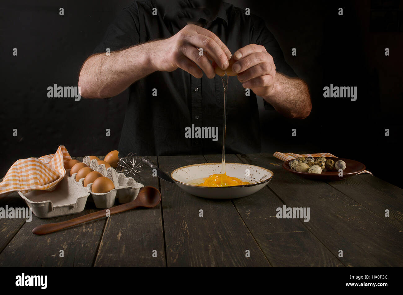 Man hands cracking an egg on a black background Stock Photo - Alamy
