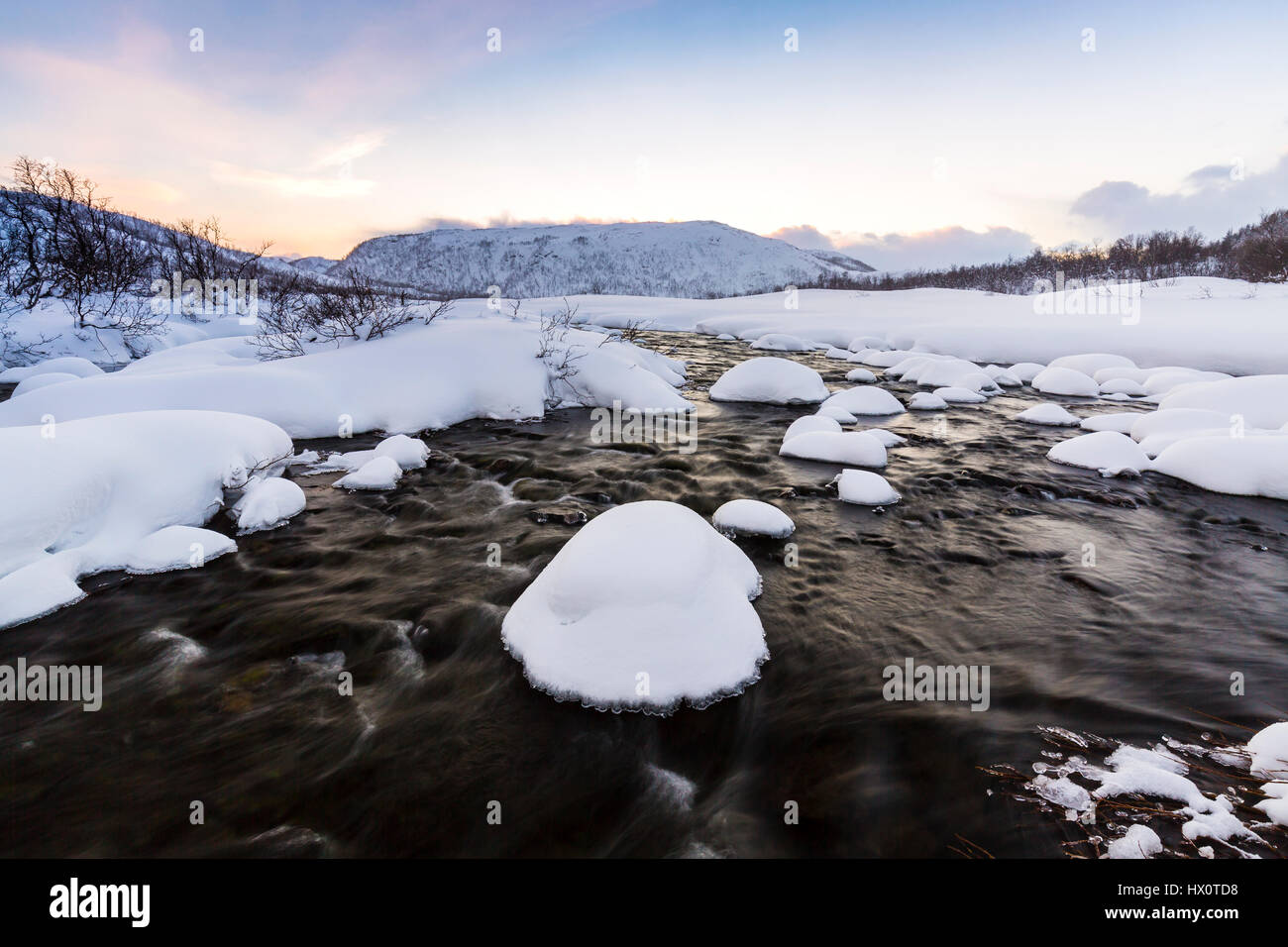 A little water stream with rocks on the foreground with a artic, snowy ...