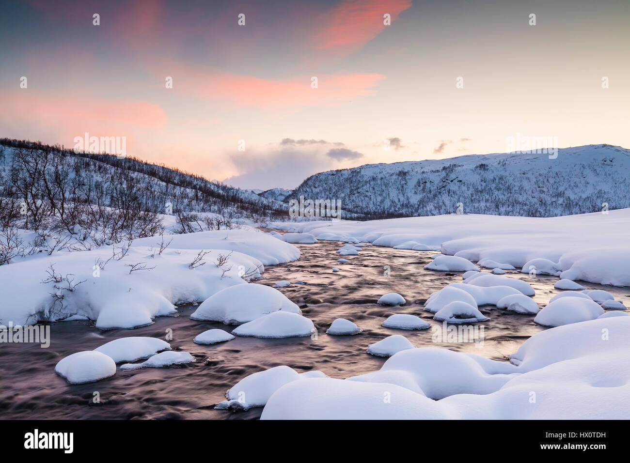 A little water stream with rocks on the foreground with a artic, snowy ...