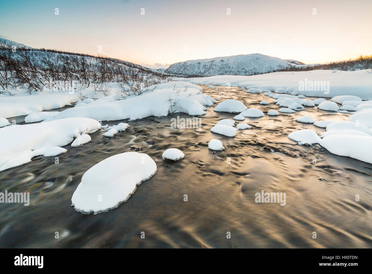 A little water stream with rocks on the foreground with a artic, snowy ...