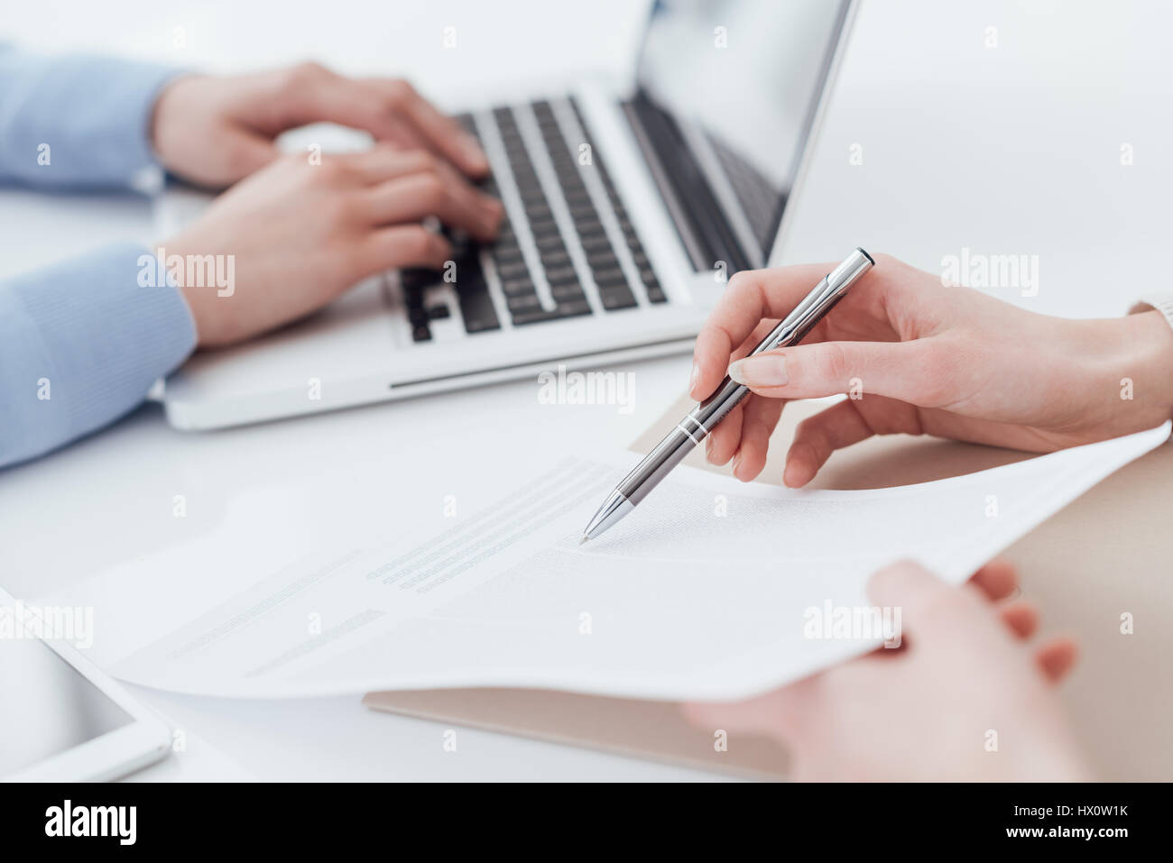 Business meeting in the office, a businesswoman is typing on a laptop ...