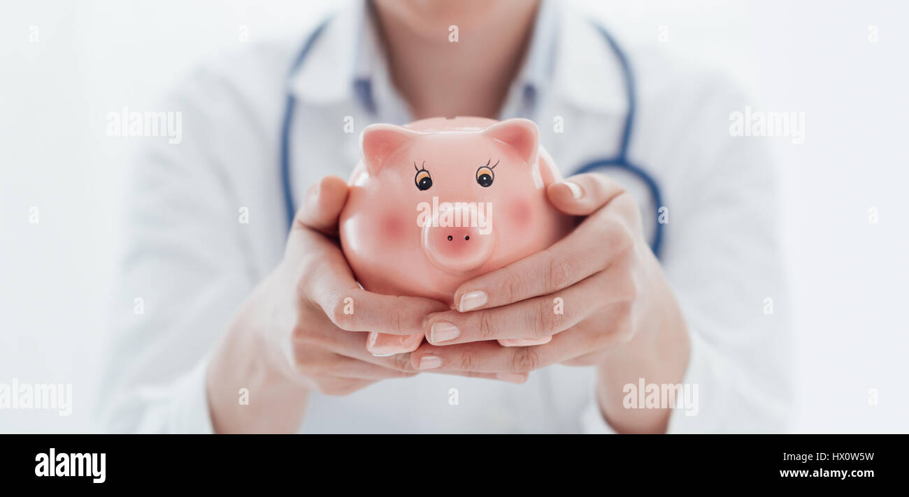 Female doctor holding a piggy bank: health insurance, medical expenses ...