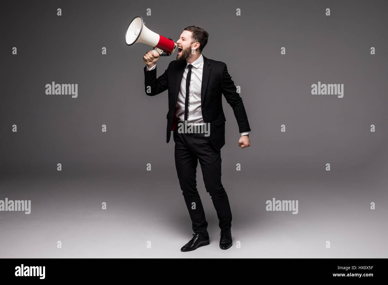 Business man screaming with a megaphone on grey background Stock Photo ...