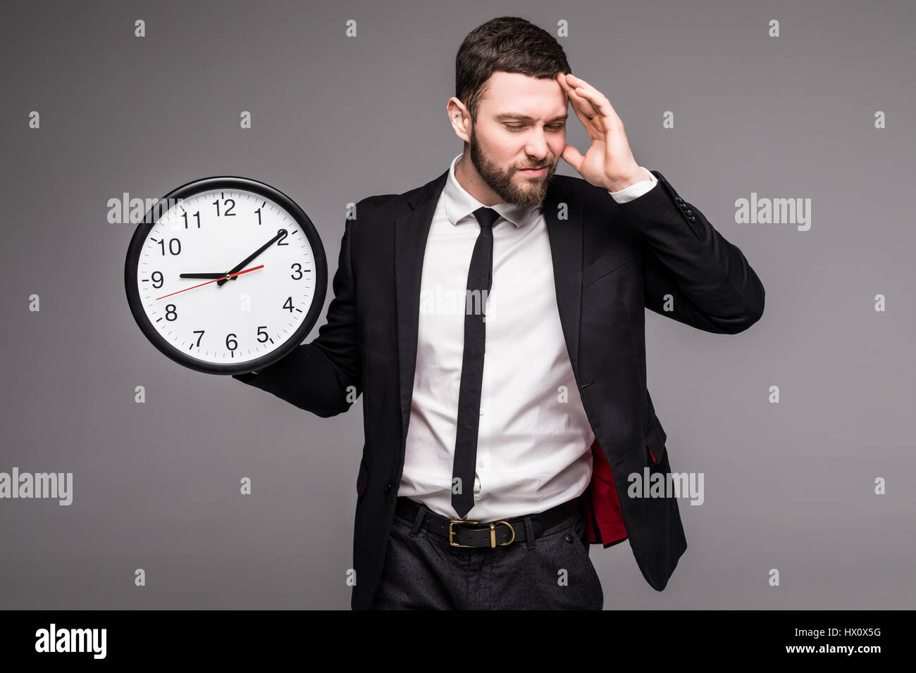 Handsome business man with clock in hand, sad beasy with time on grey ...