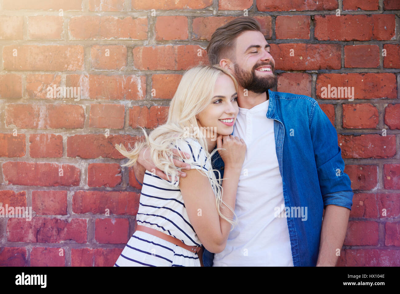 Embracing couple standing in front of brick wall Stock Photo - Alamy