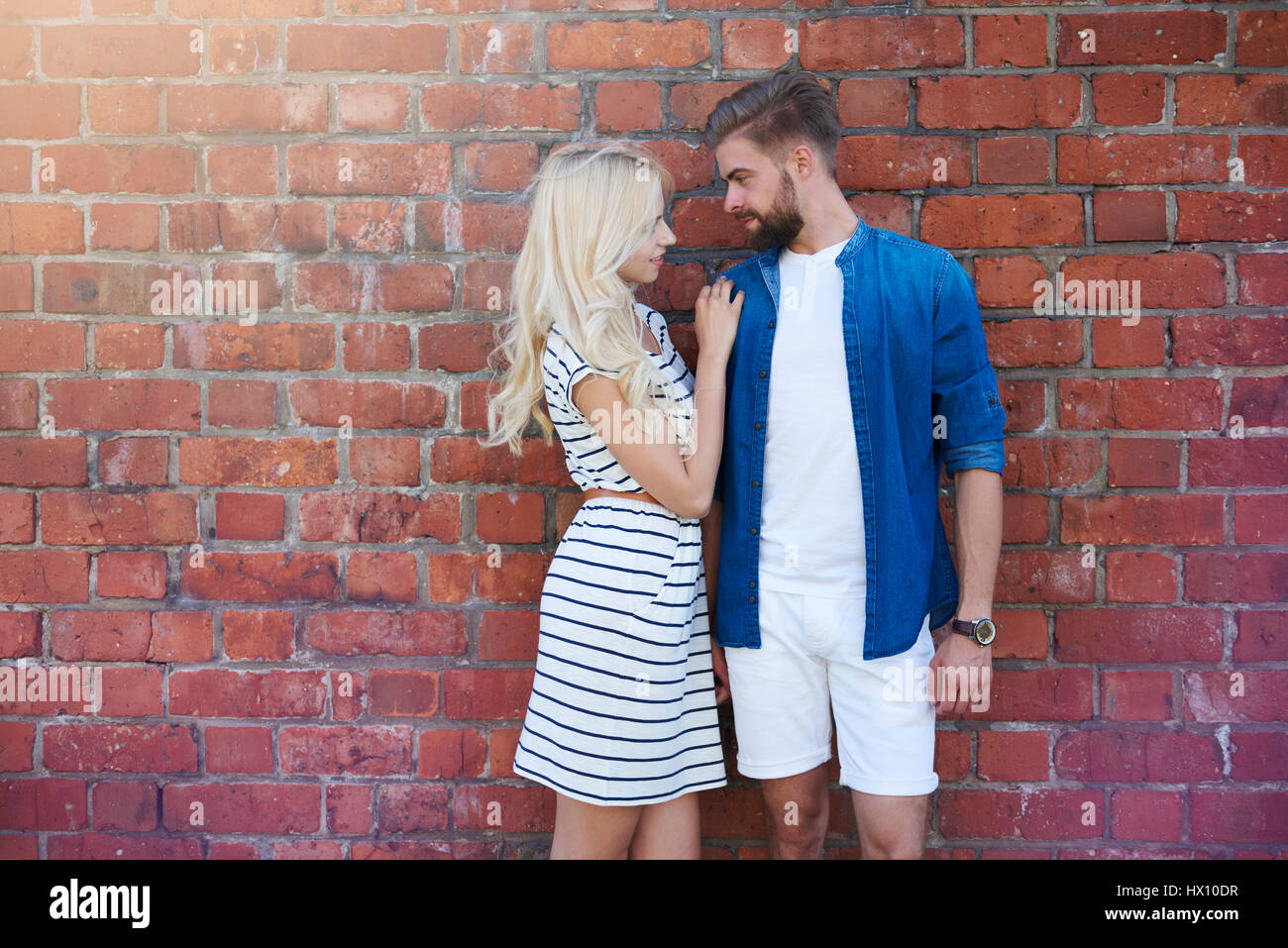 Loving couple standing in front of brick wall Stock Photo - Alamy