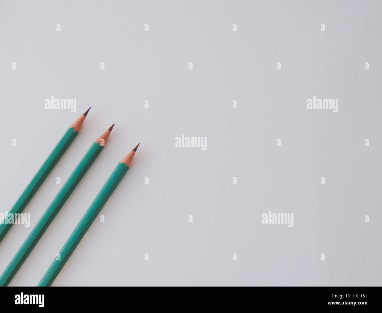 Three identical pencils lying on a plain background Stock Photo - Alamy