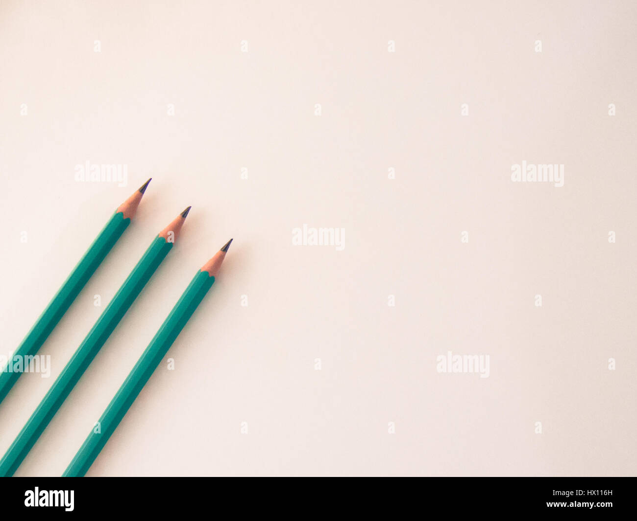 Three identical pencils lying on a plain background Stock Photo - Alamy