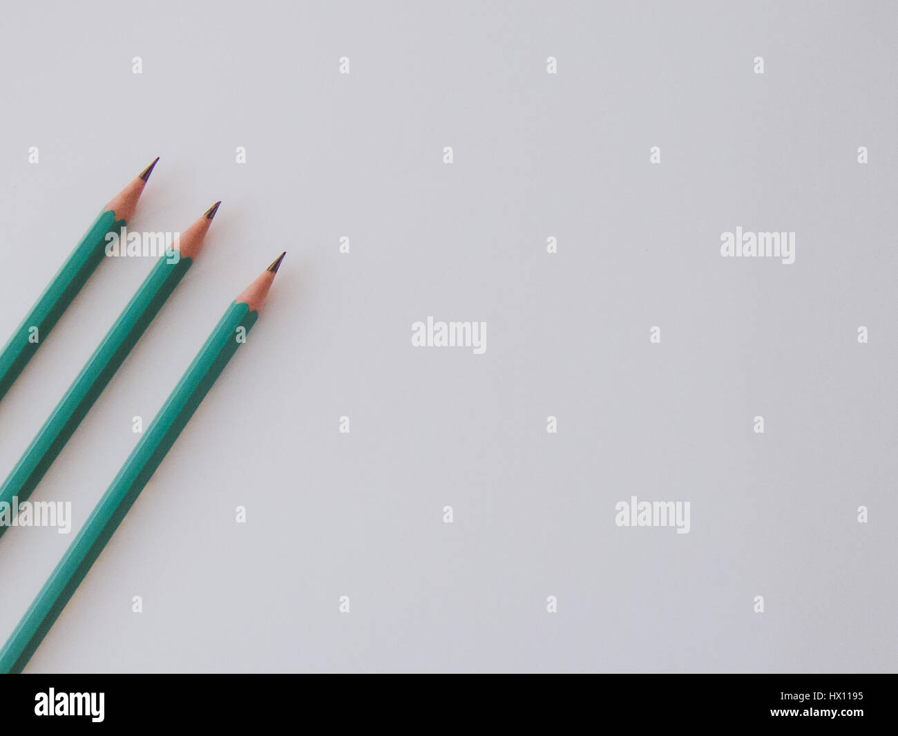 Three identical pencils lying on a plain background Stock Photo - Alamy