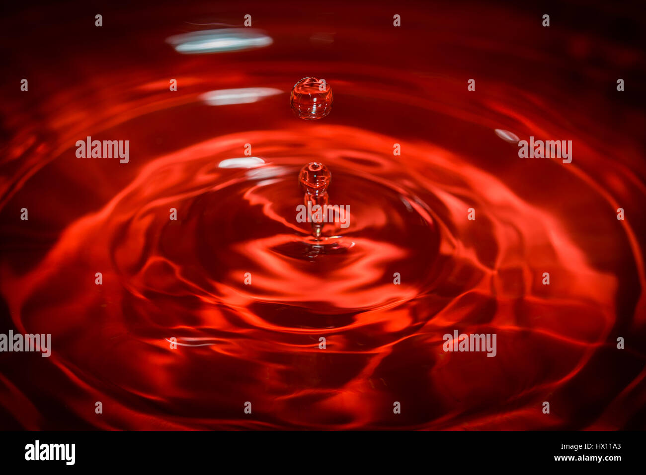 Water drop an waves with red background and reflection Stock Photo - Alamy