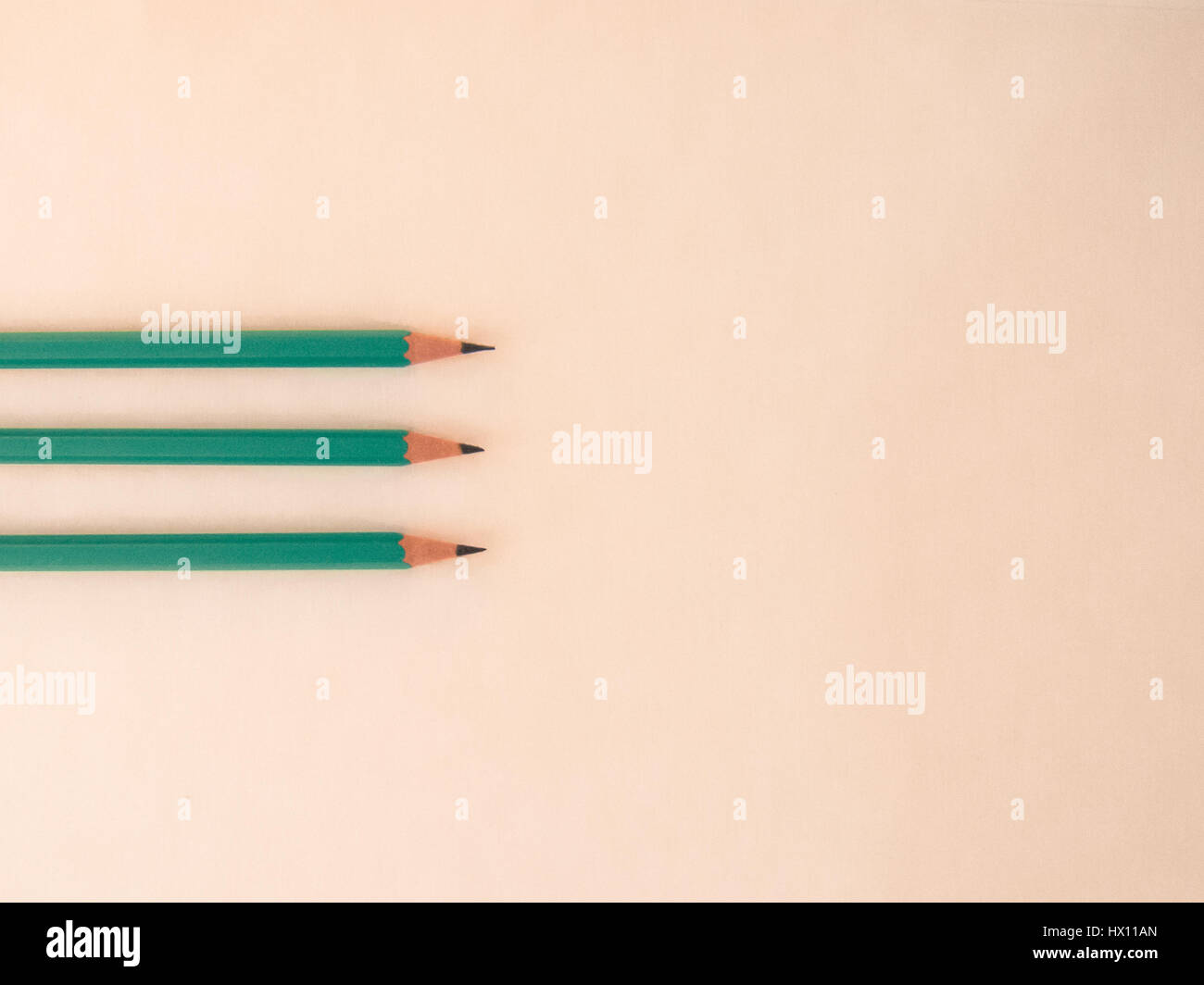 Three identical pencils lying on a plain background Stock Photo - Alamy