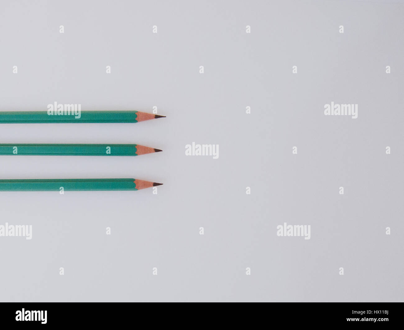 Three identical pencils lying on a plain background Stock Photo - Alamy