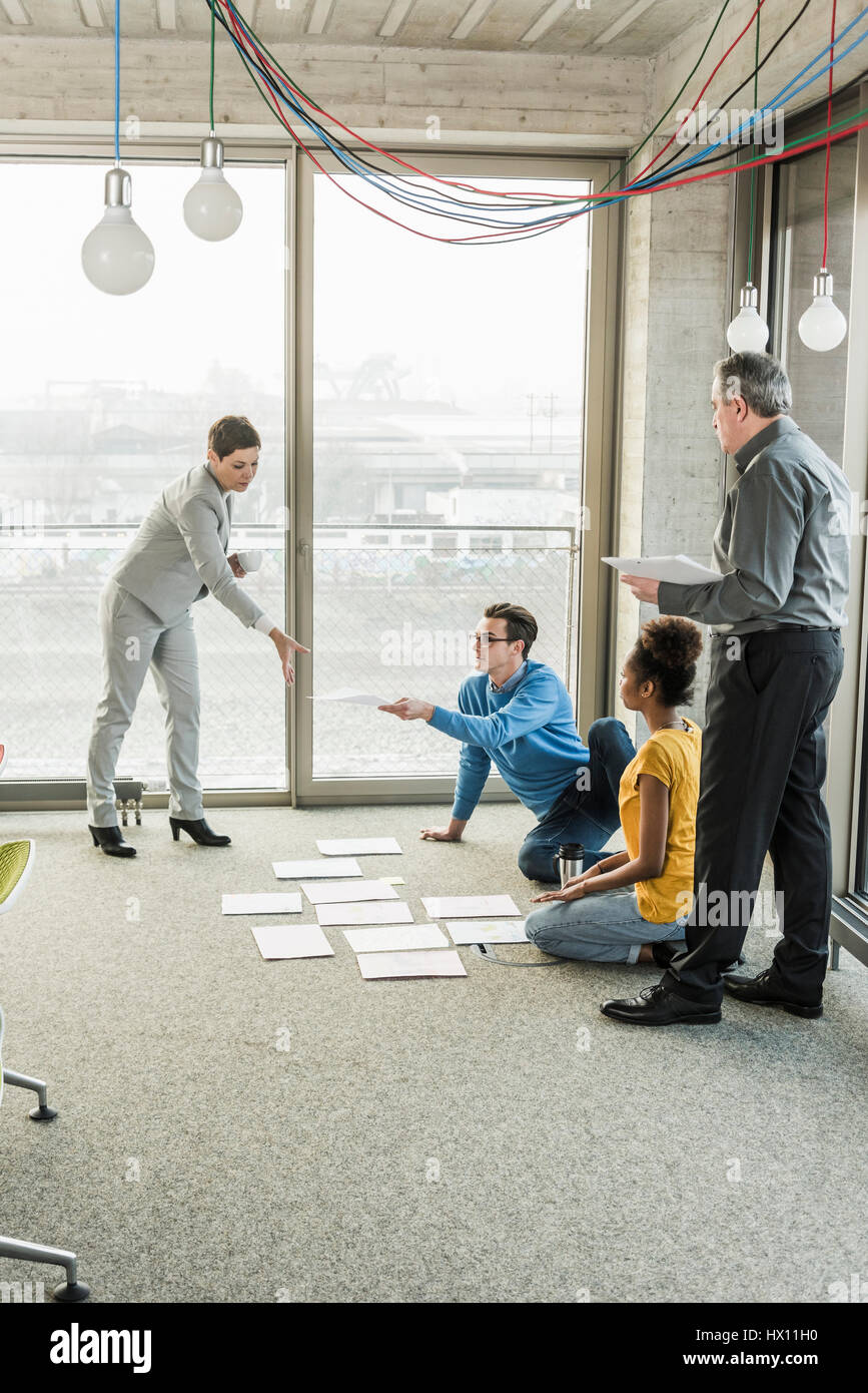 Businesspeople looking at documents on office floor Stock Photo - Alamy